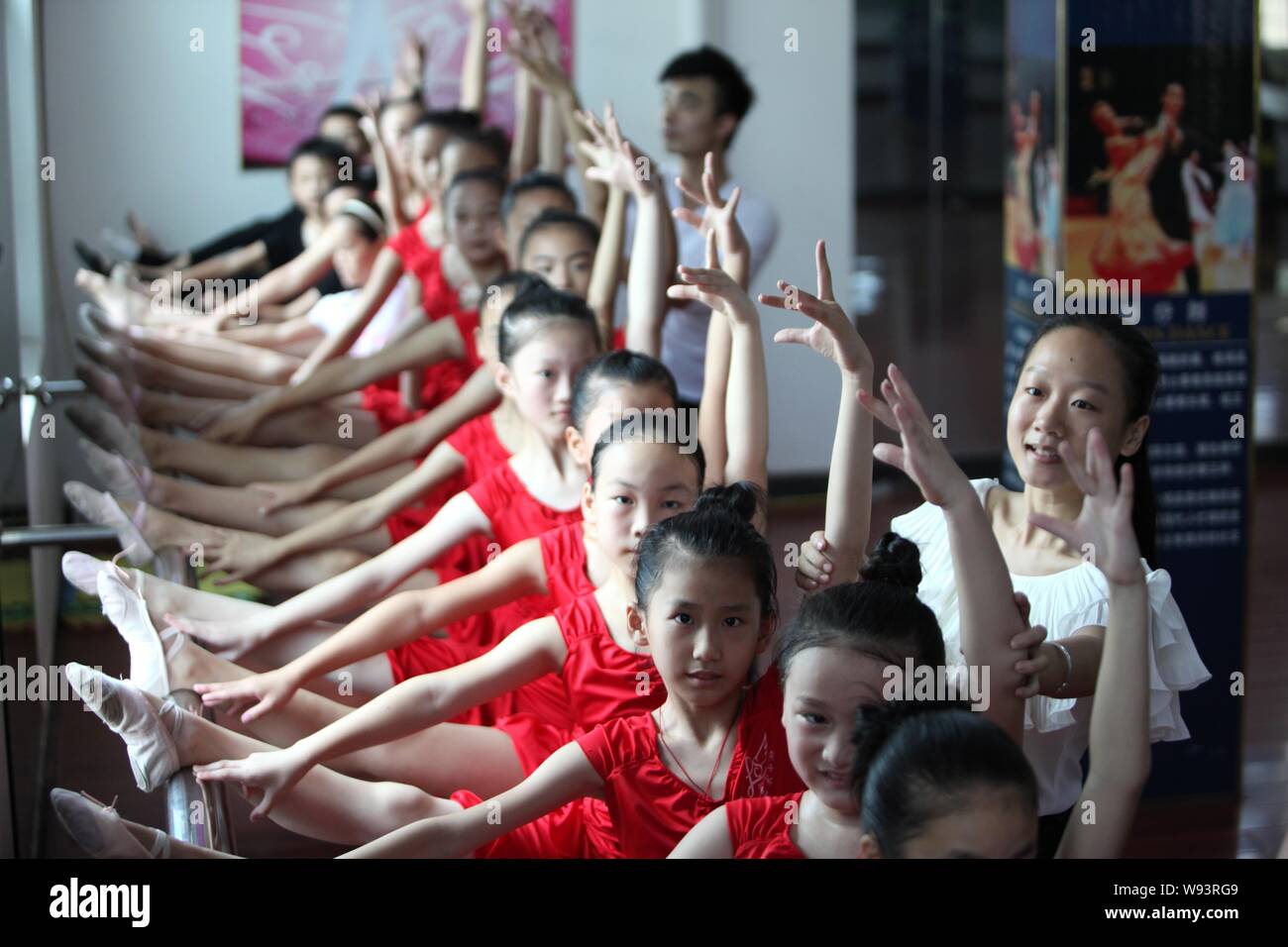 A teacher adjusts the posture of a young Chinese girl studying ballet ...