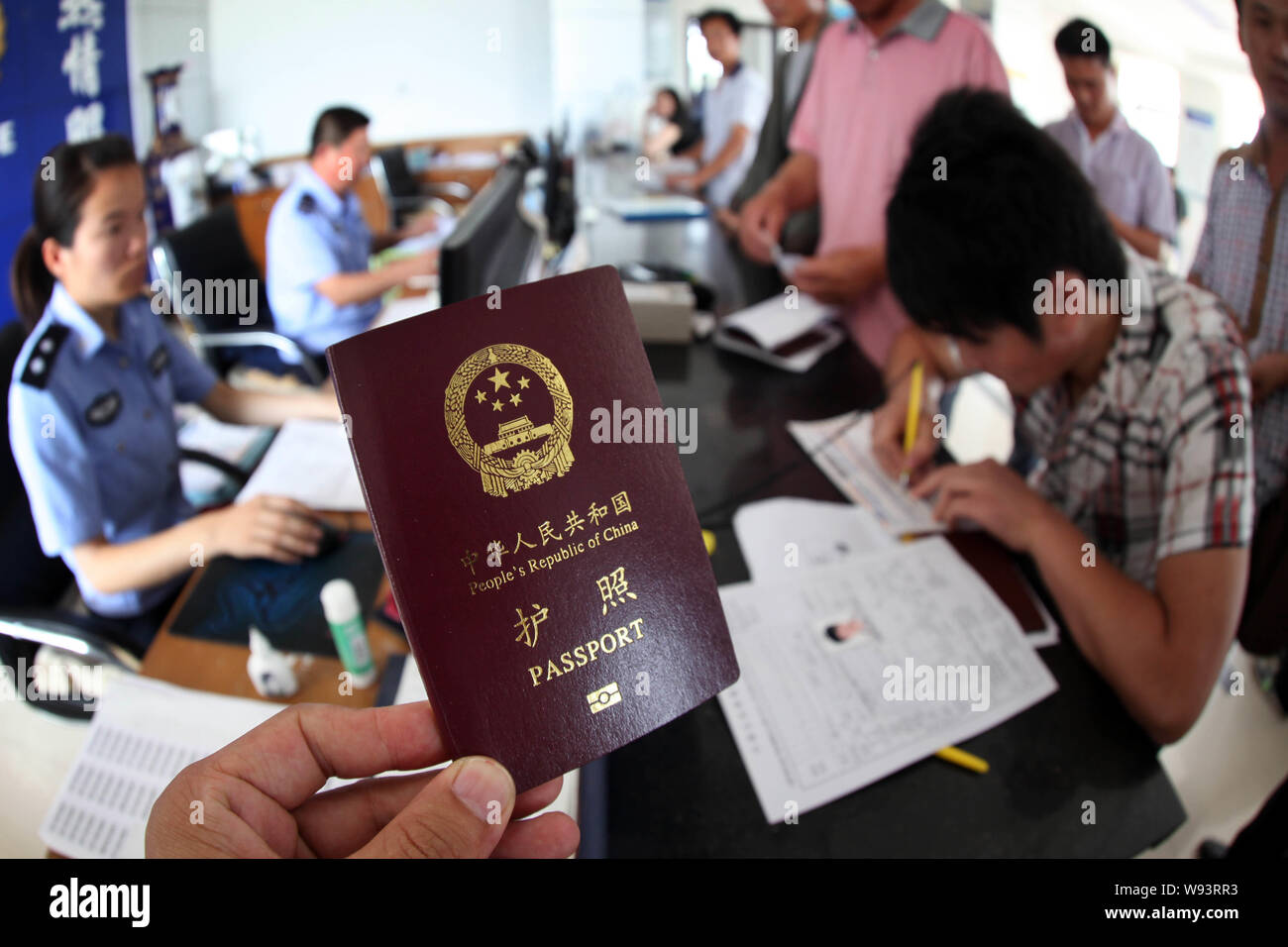 --FILE--A local resident shows his passport as another fills in forms ...