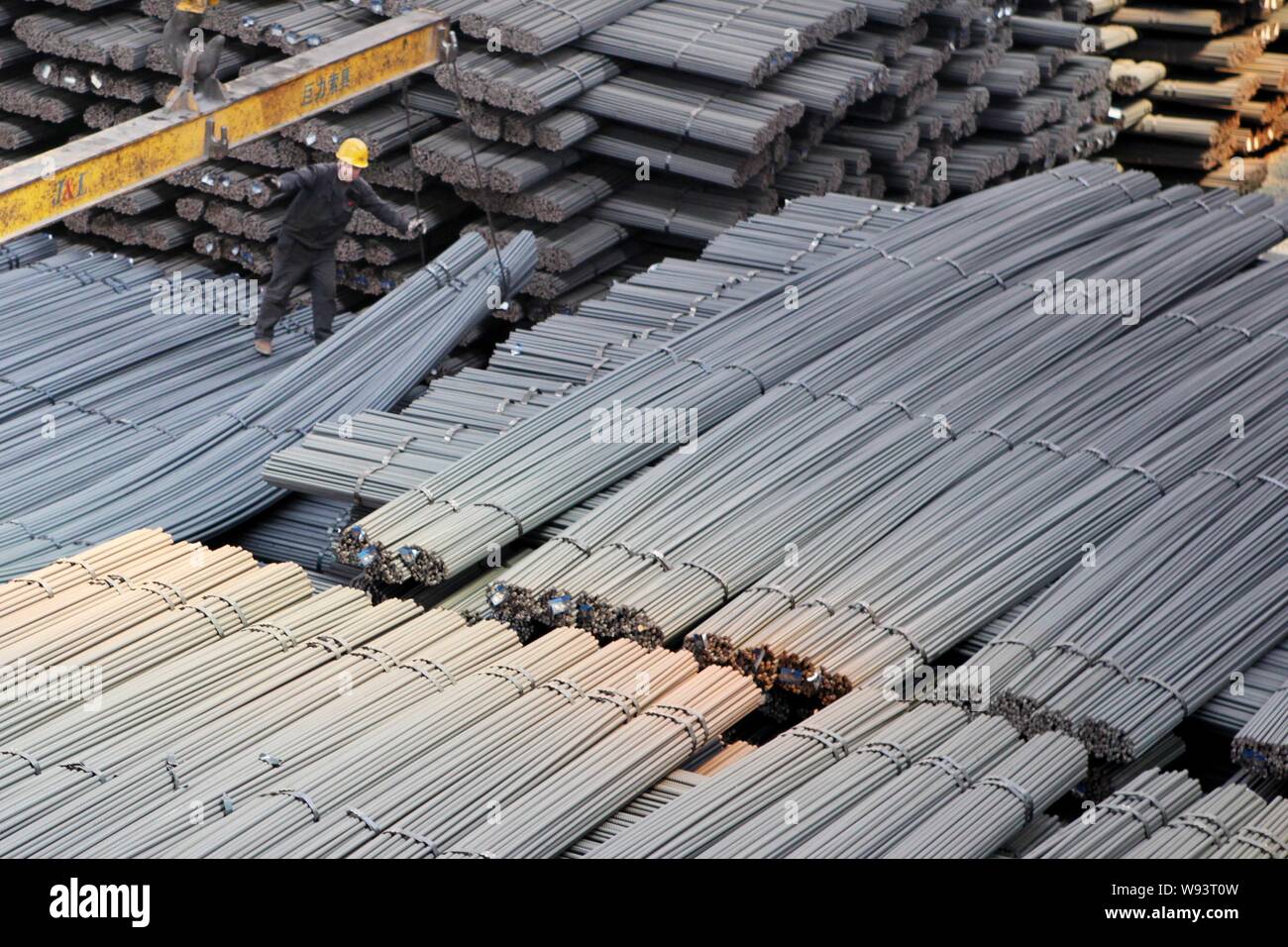 --FILE--A Chinese worker directs a crane to lift reinforcing steel rods ...