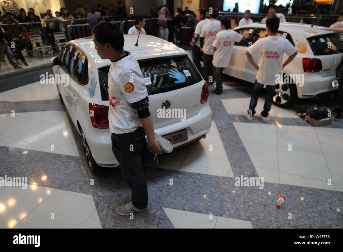 A Chinese contestant relaxes his leg next to others as they keep their ...
