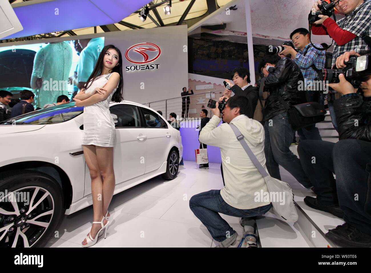 Visitors take photos of a model at the stand of Soueast during the 15th ...