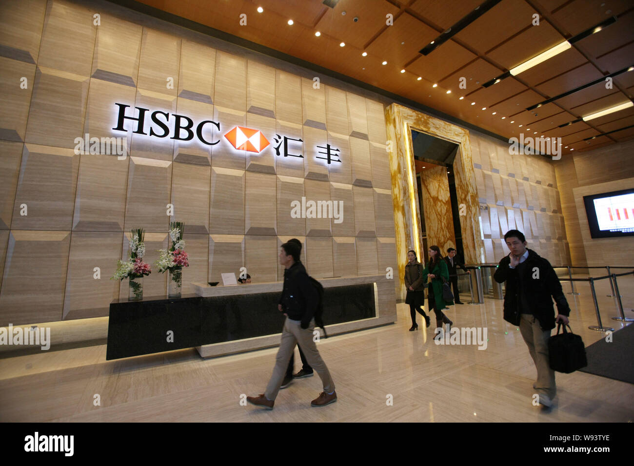 --FILE--People walk past the front desk at the China headquarters of ...
