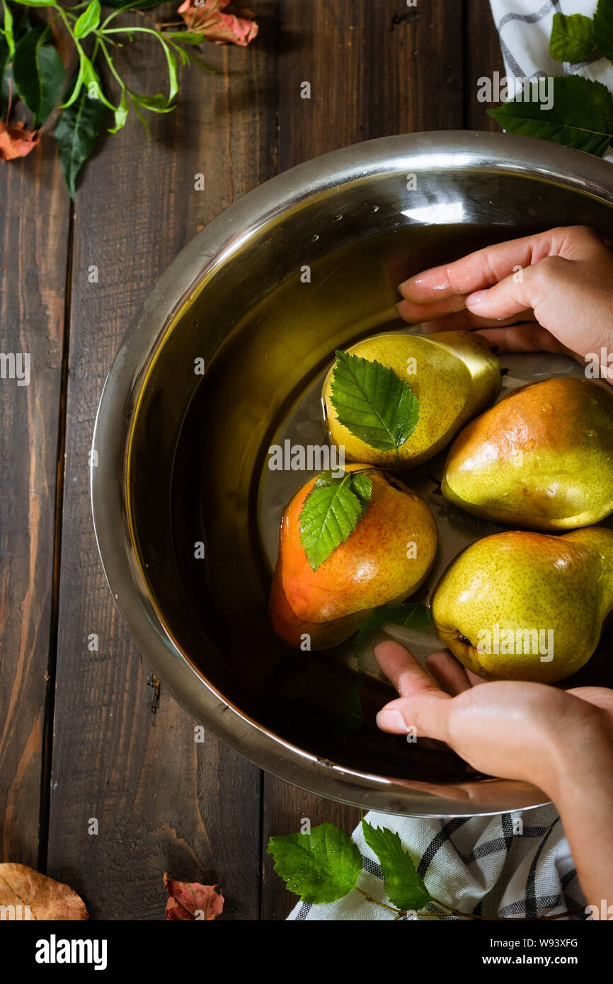 Female hands wash an organic pear crop in a tin basin. Farm harvest ...