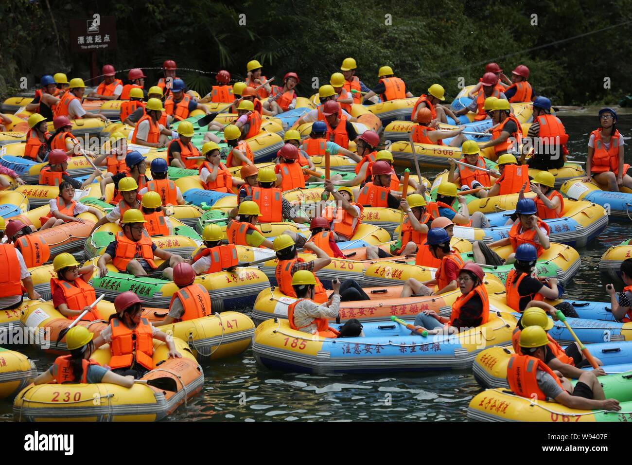 A crowd of holidaymakers sitting in life rafts wait for a waterfall ...