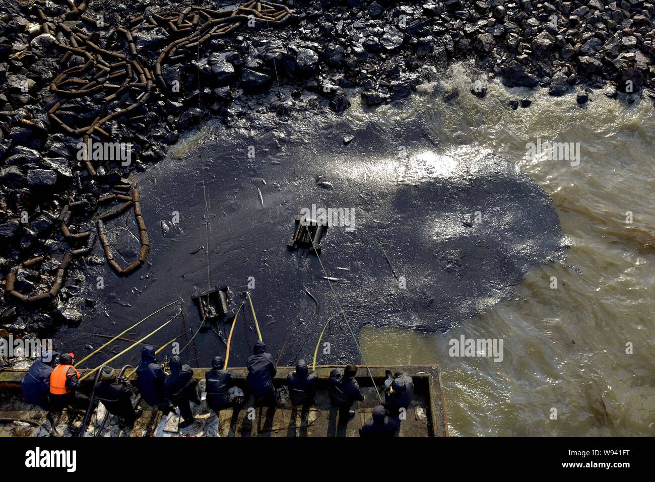Chinese workers clean up leaked oil after the oil pipeline explosion in ...