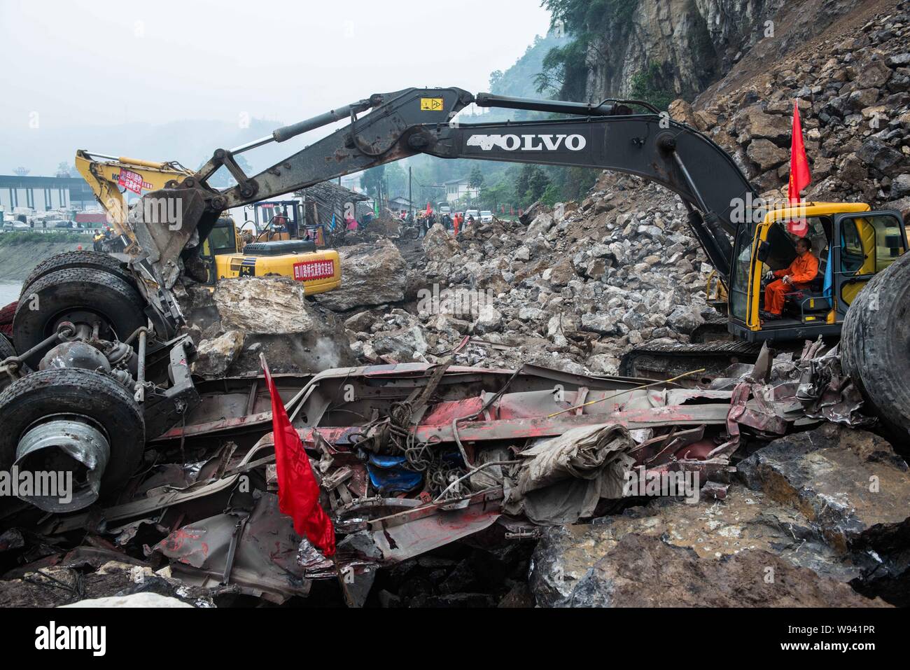 Rescuers operate excavators to clear rocks and the wreckage of a truck ...