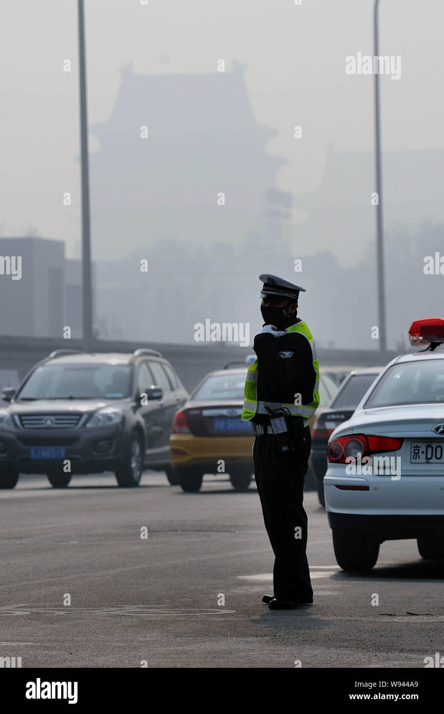 A police officer wearing a face mask directs cars on a road in heavy ...