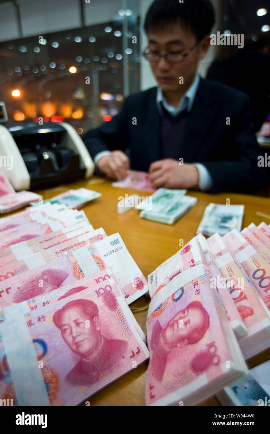 --FILE--A Chinese clerk counts RMB (renminbi) yuan banknotes at a bank ...