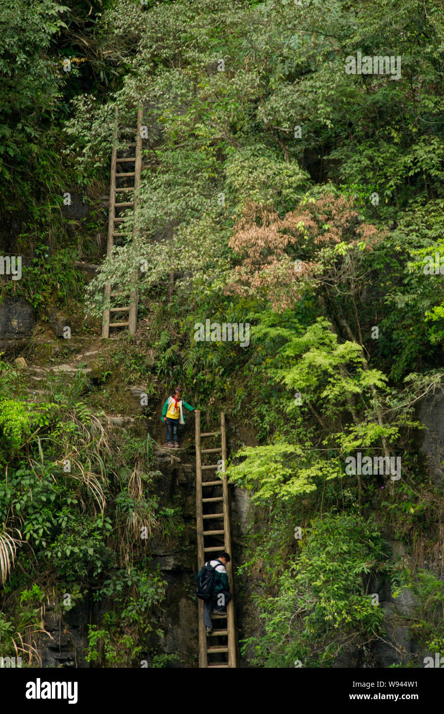 View of people climbing two vertical wooden ladders in deep mountains ...