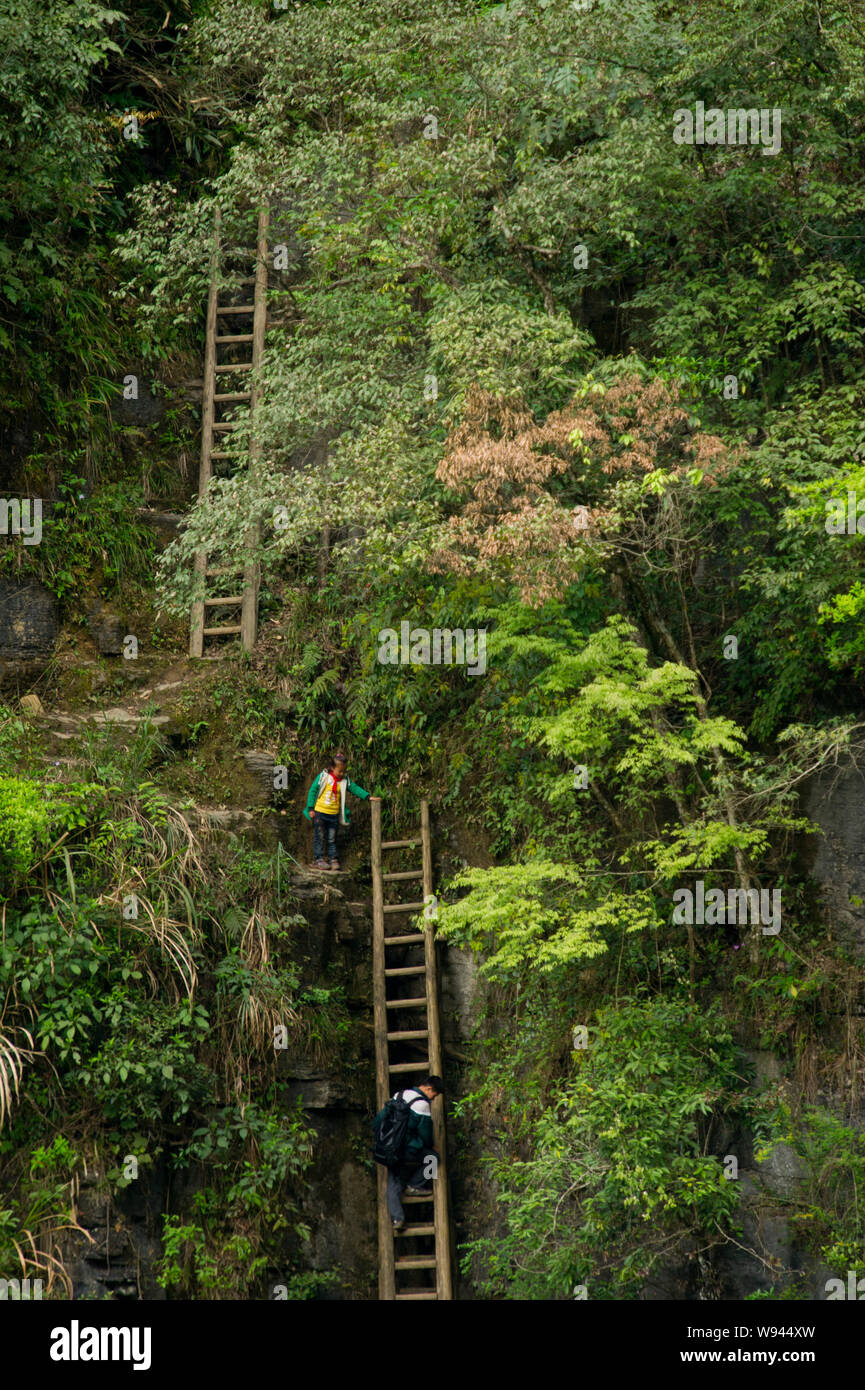 View of people climbing two vertical wooden ladders in deep mountains ...