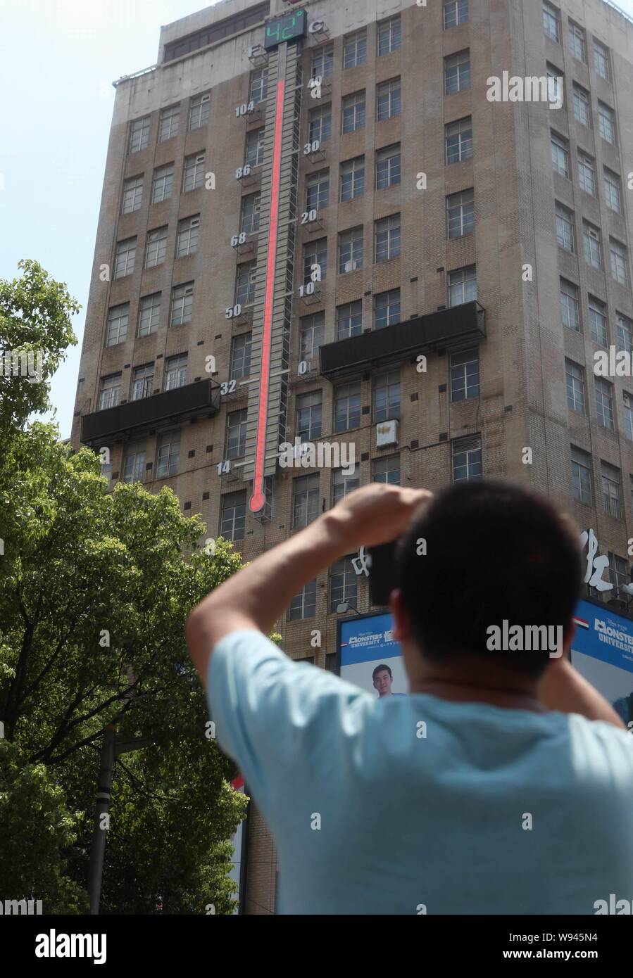A pedestrian takes photos of a giant thermometer showing the current ...