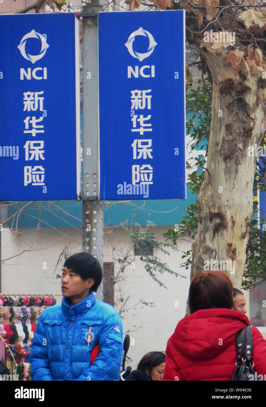 --FILE--Pedestrians walk past an advertisement of NCI (New China Life ...