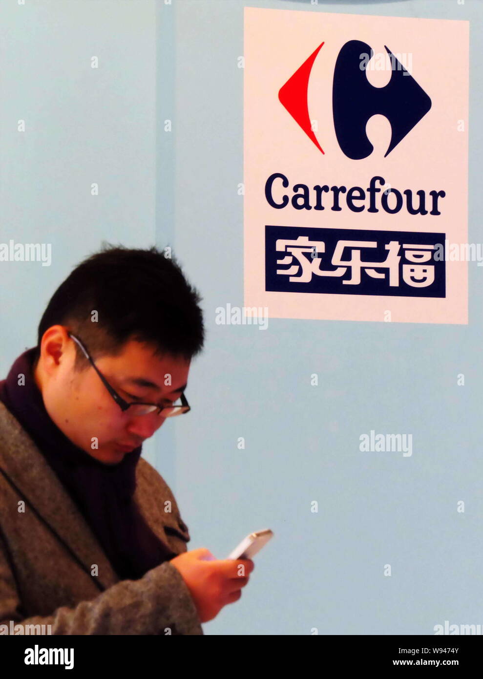 --FILE--A customer uses his mobile phone as he walks past a logo of ...