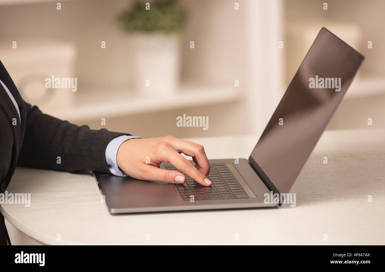 Business woman below chest working on her laptop in a cozy environment ...