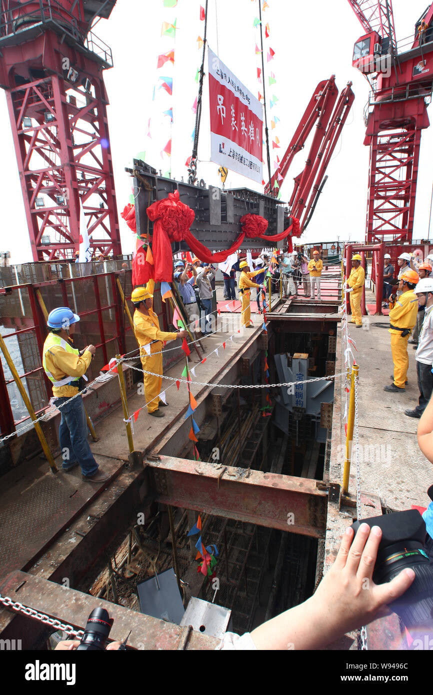 The final steel beam is lifted onto the top of the Shanghai Tower ...