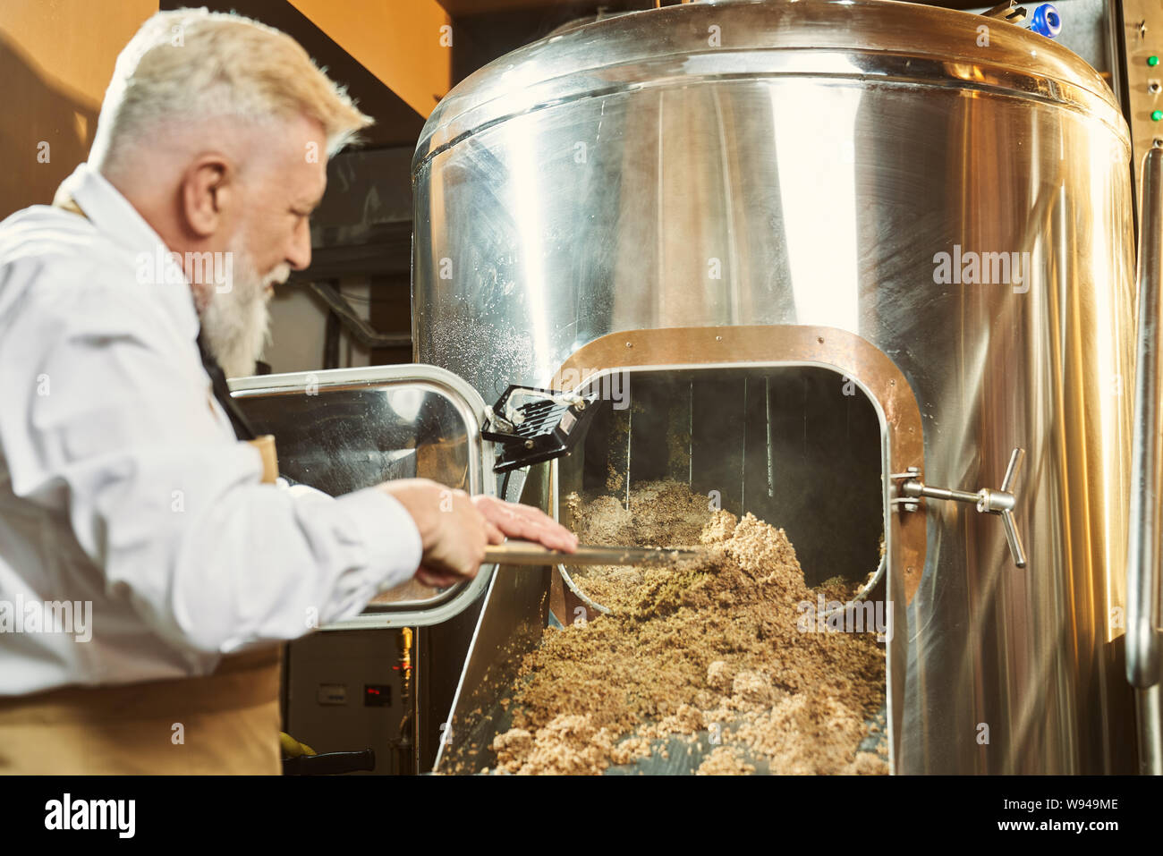 View from back of man keeping shovel and examining quality of grist in ...