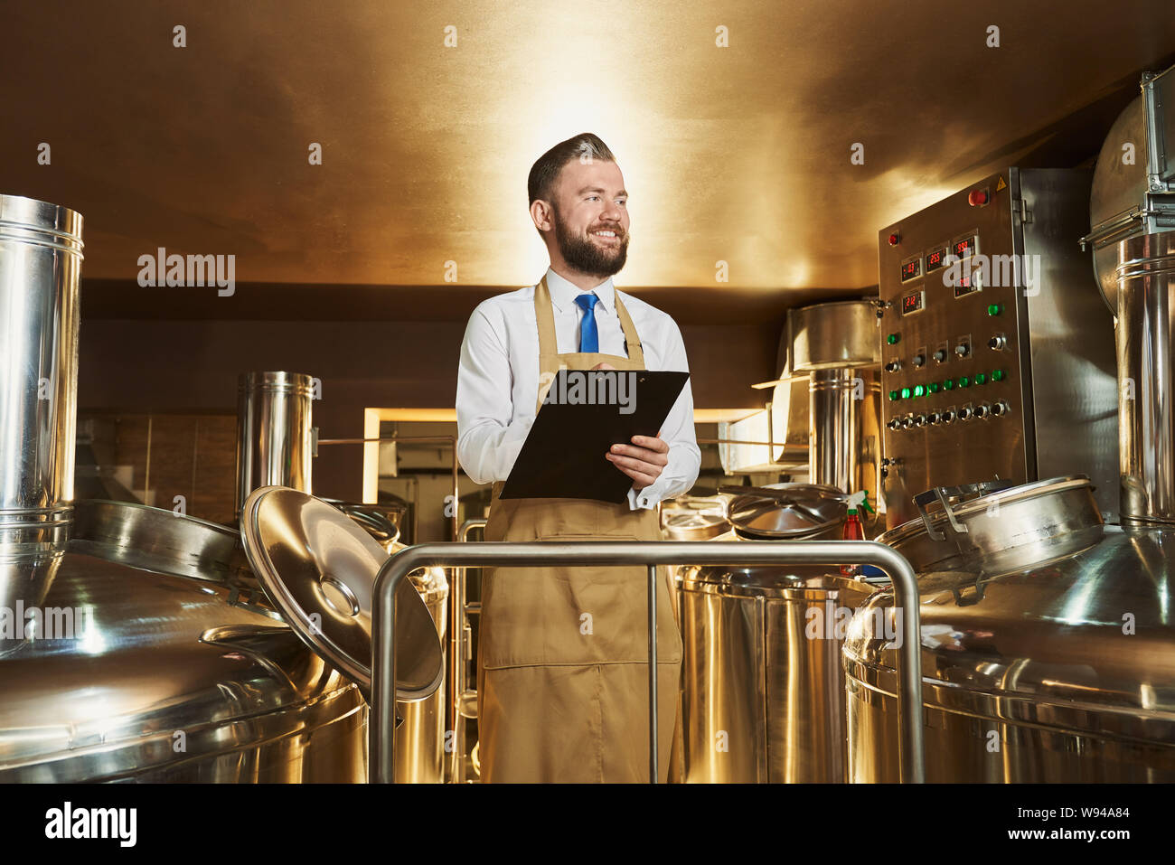 Front view of happy male brewer keeping folder and laughing while ...