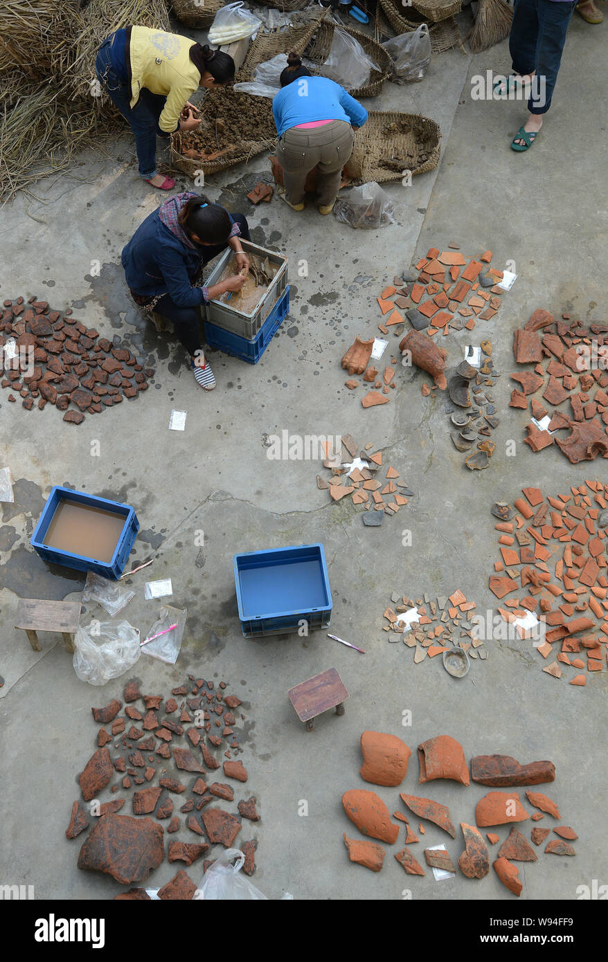 Chinese workers clean up broken pieces of pottery wares unearthed from ...