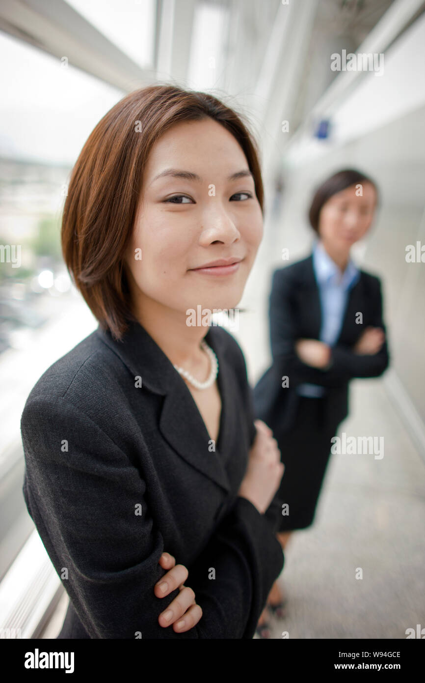 Portrait of Chinese businesswoman with her colleague in the background ...