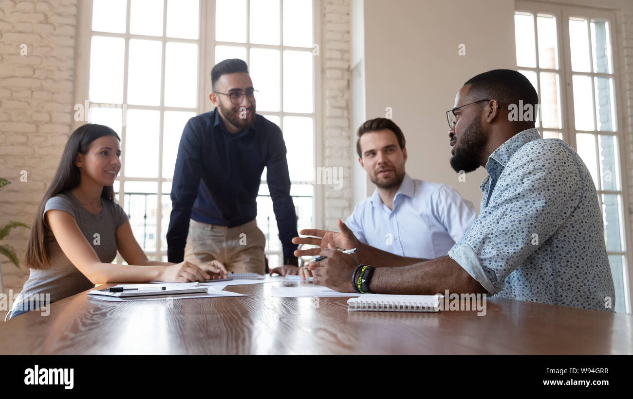 Happy multiracial team listening african colleague at corporate ...