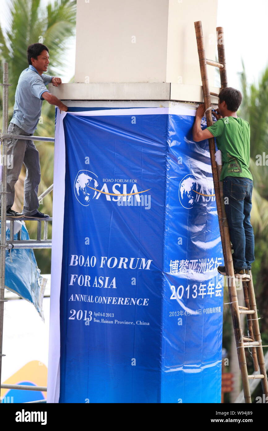 Workers set up posters of Boao Forum for Asia at the Asia International ...
