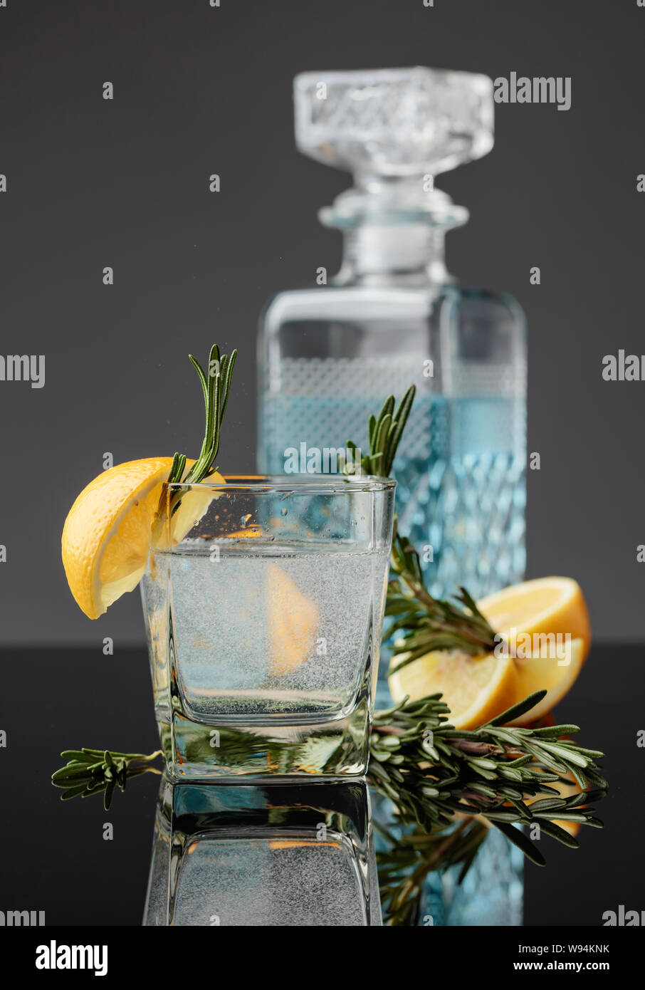 Cocktail gin-tonic with lemon slices and twigs of rosemary on a black ...
