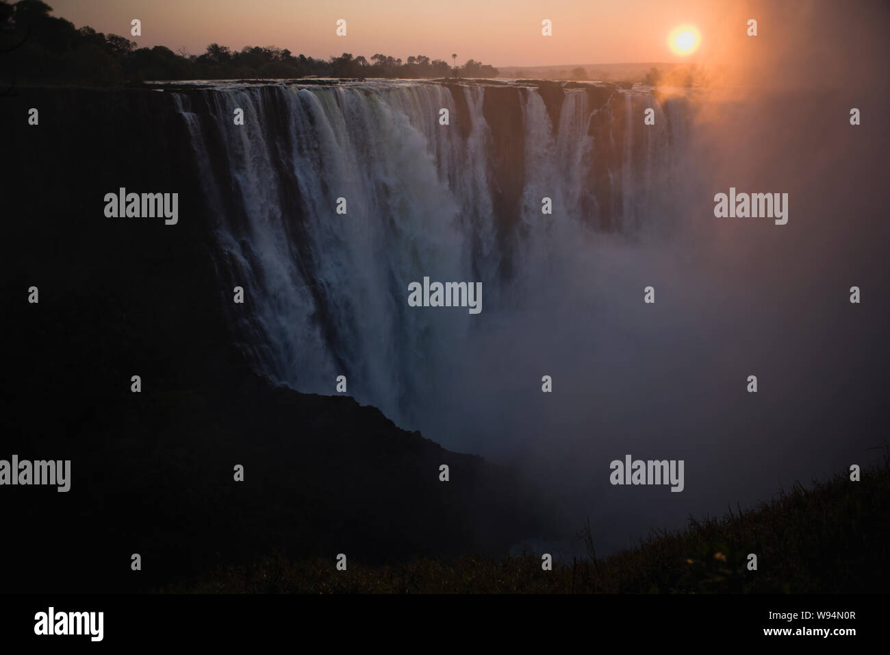 Mist rising from a huge waterfall at sunset Stock Photo - Alamy