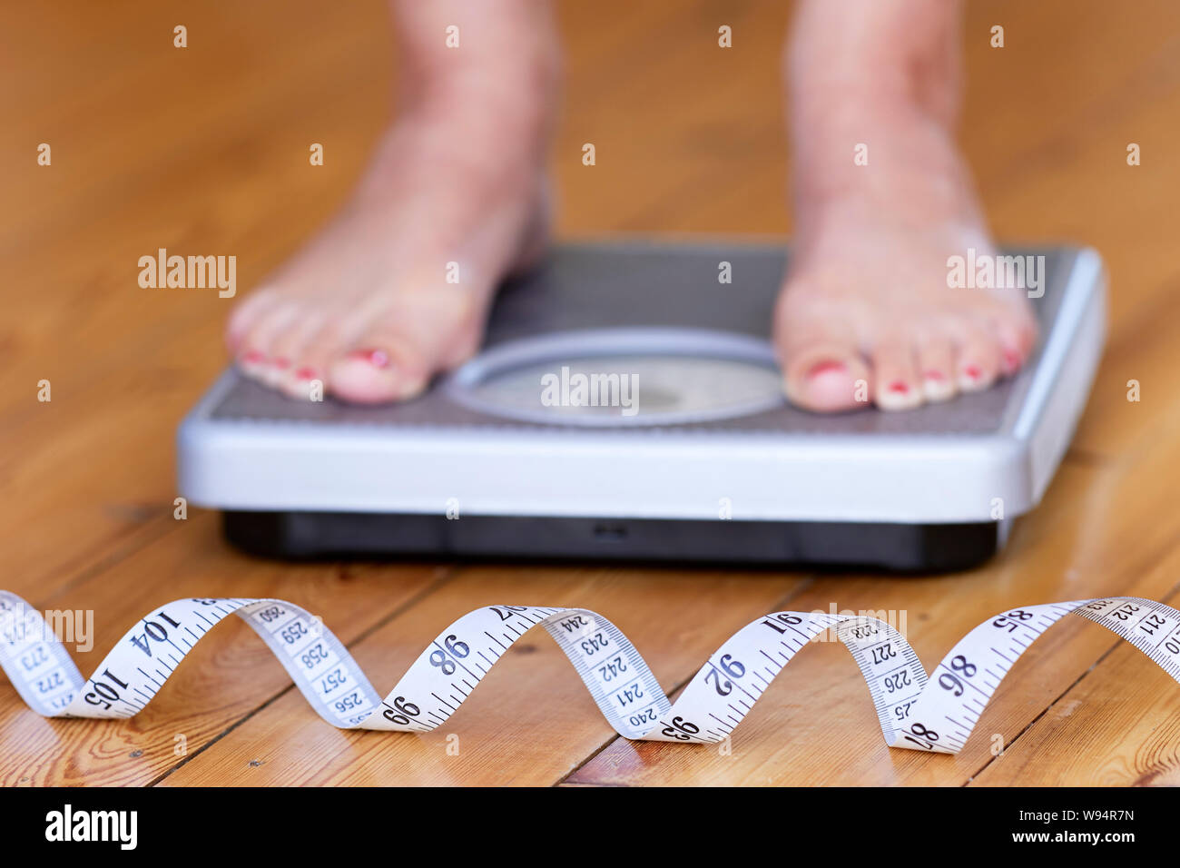 Person stood on scales weighing themselves Stock Photo - Alamy