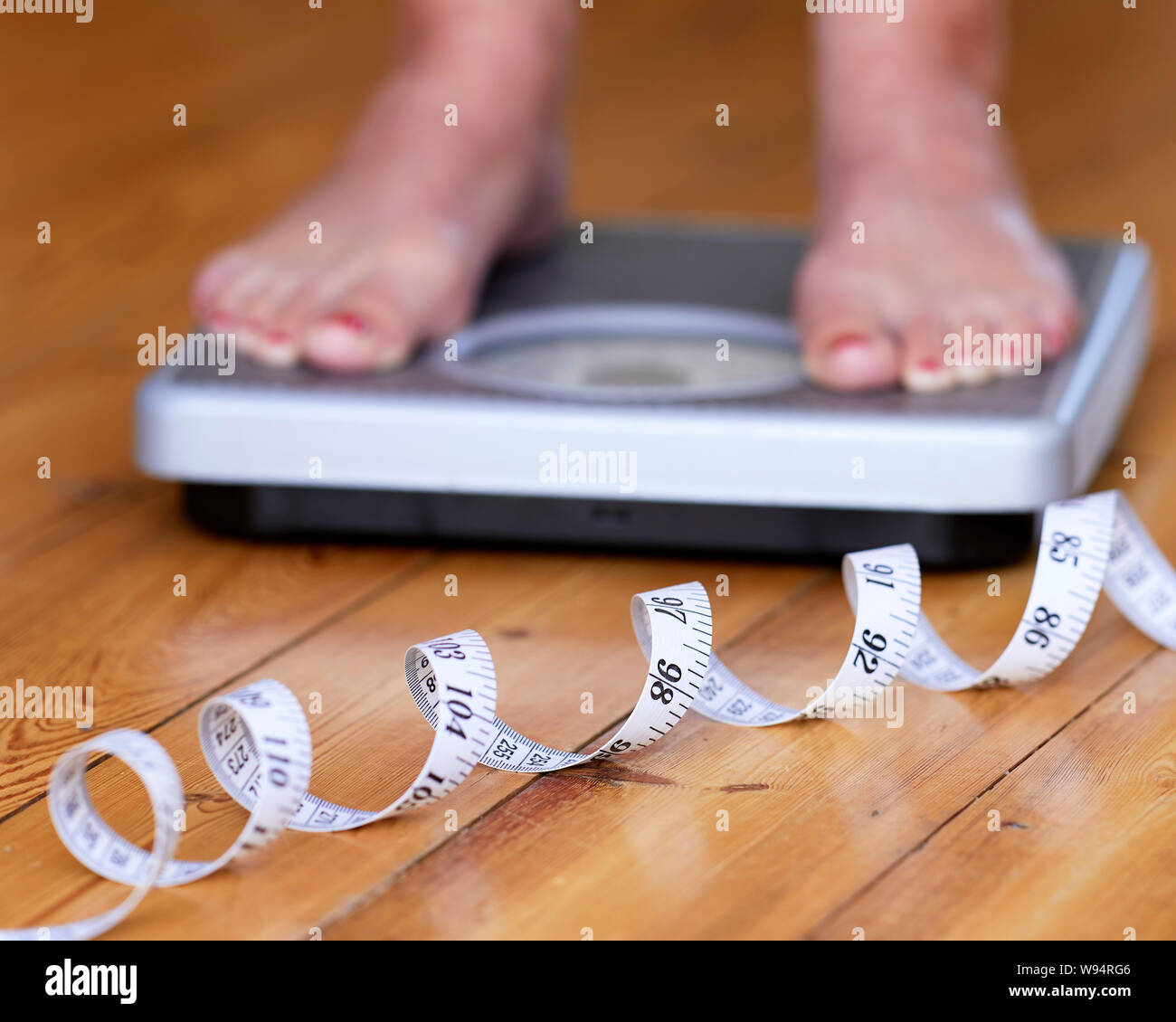 Person stood on scales weighing themselves Stock Photo - Alamy