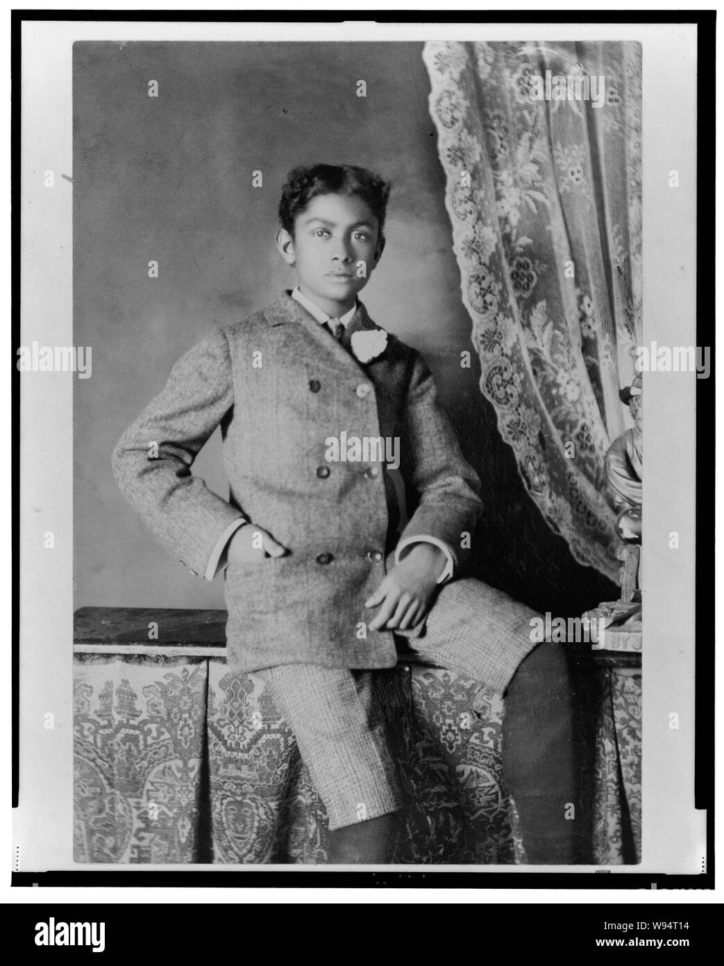 African American boy, three-quarter-length portrait, half-sitting on ...