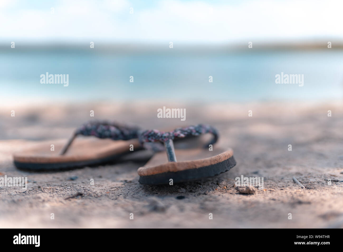Pair of slippers on the sand at the beach while a blurry background ...