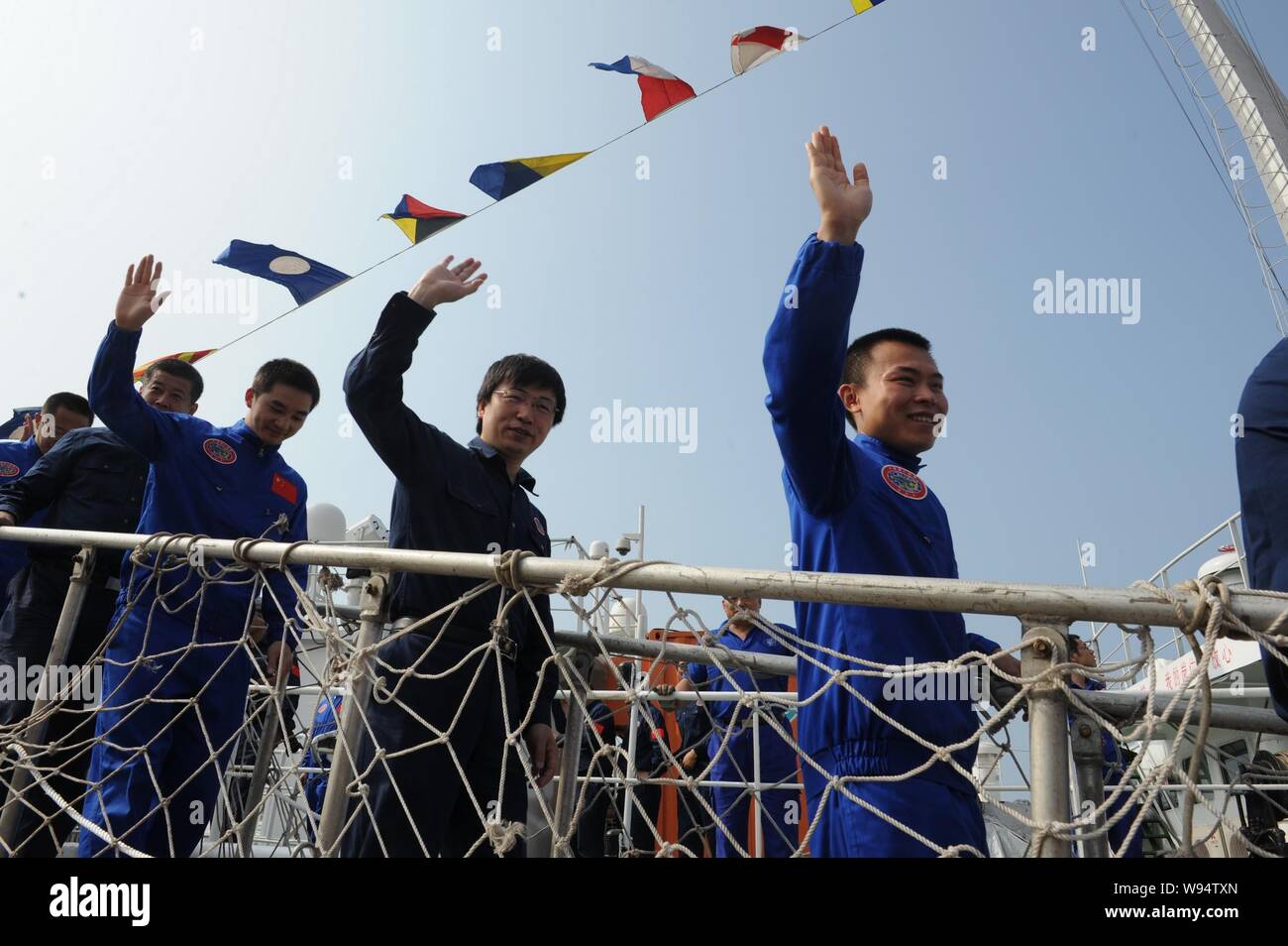 Chinese staff members wave on the oceanographic ship Xiangyanghong 09 ...