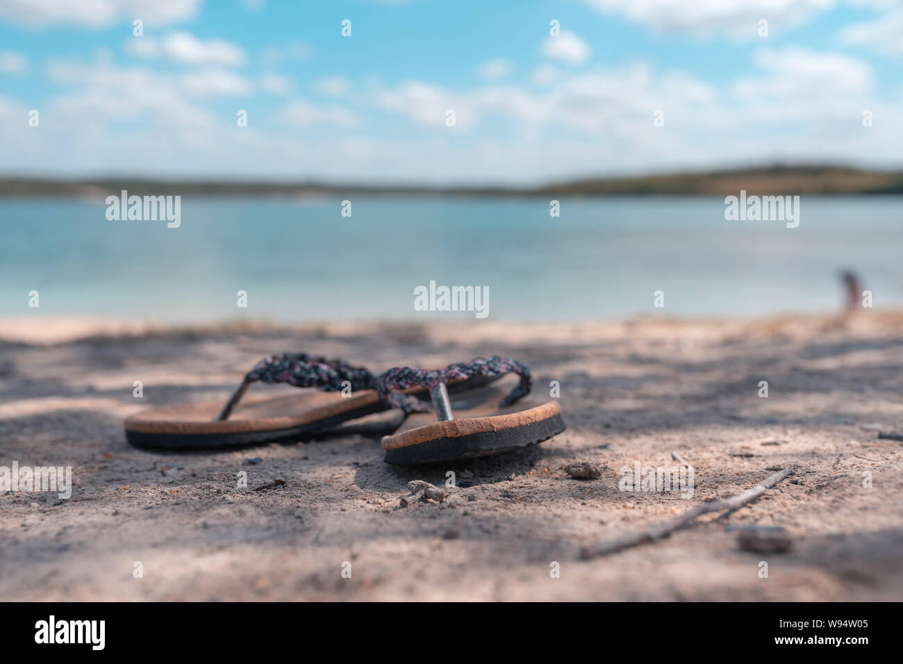 Pair of slippers on the sand at the beach while a blurry background ...