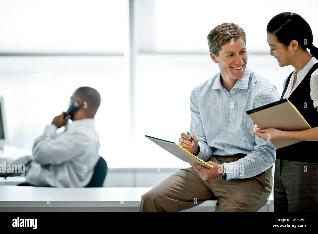 Office workers looking at files together Stock Photo - Alamy