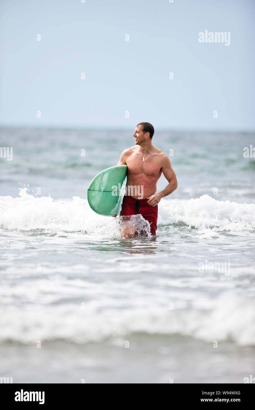 Man running along the beach with his surfboard Stock Photo - Alamy