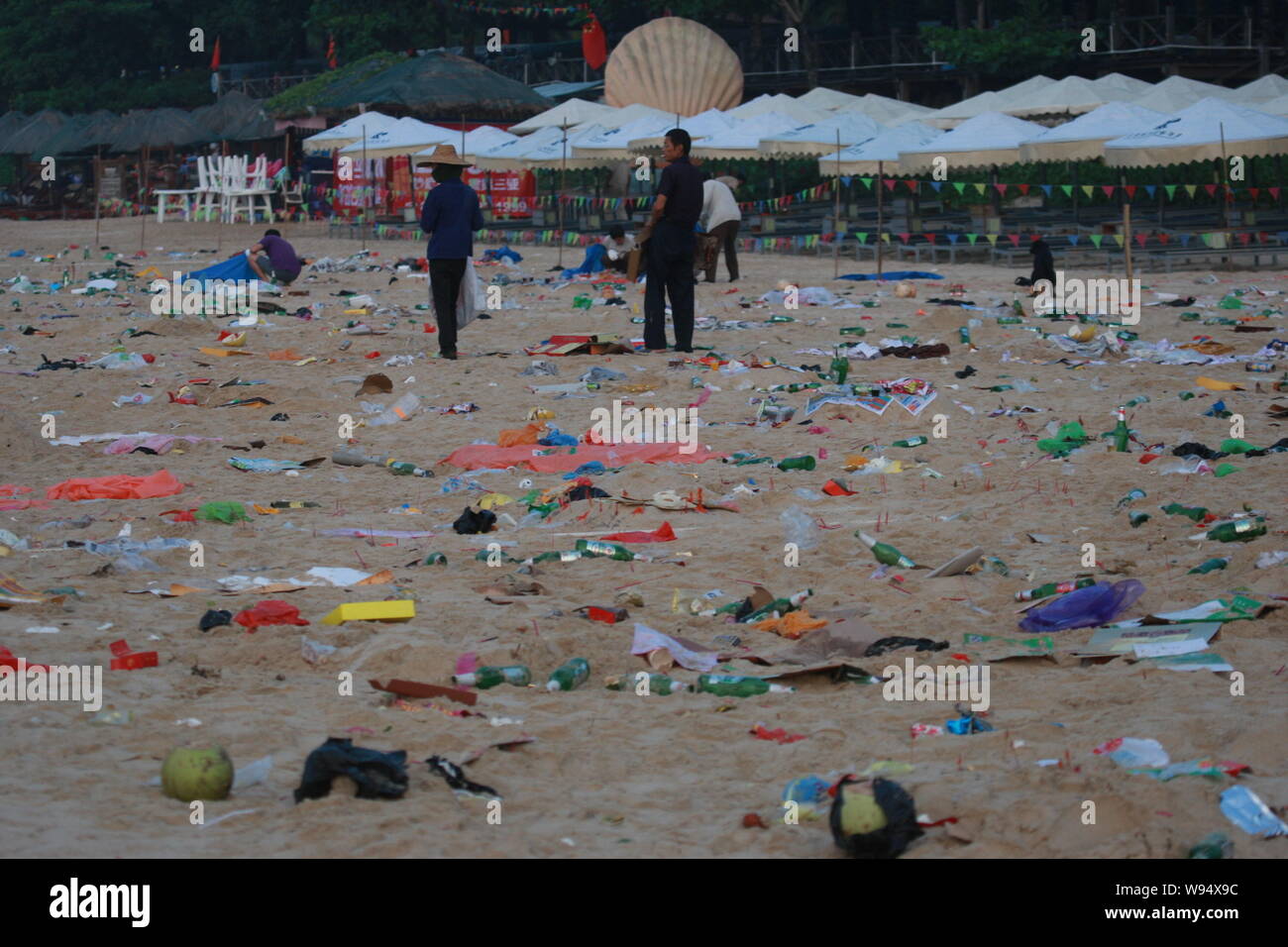 Chinese workers clean up the garbage left by tourists on a beach at the ...