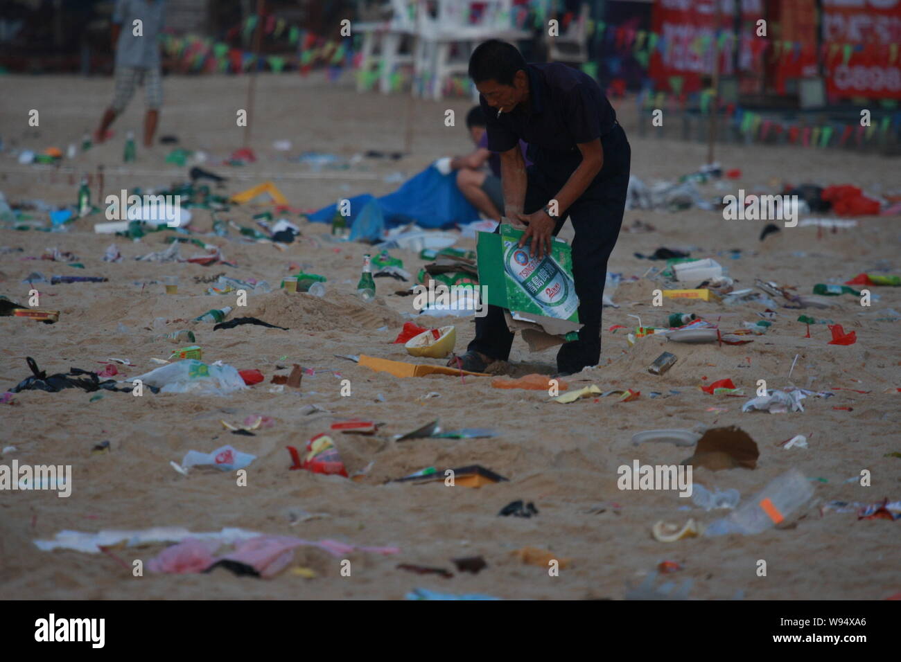 Chinese workers clean up the garbage left by tourists on a beach at the ...