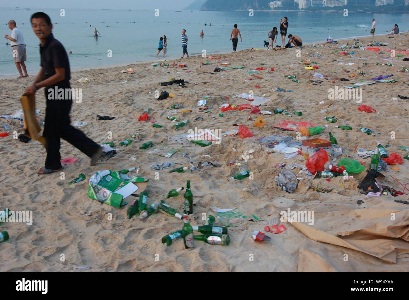 A Chinese worker cleans up the garbage left by tourists on a beach at ...