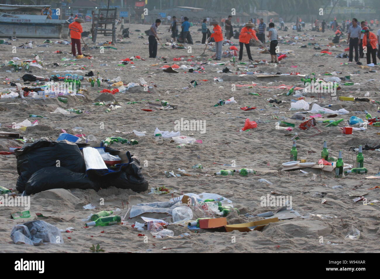 Chinese workers clean up the garbage left by tourists on a beach at the ...