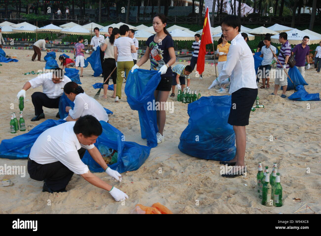 Chinese workers clean up the garbage left by tourists on a beach at the ...