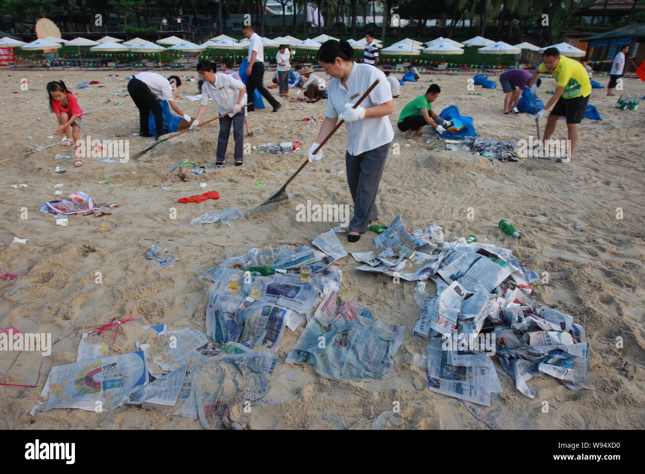 Chinese workers clean up the garbage left by tourists on a beach at the ...