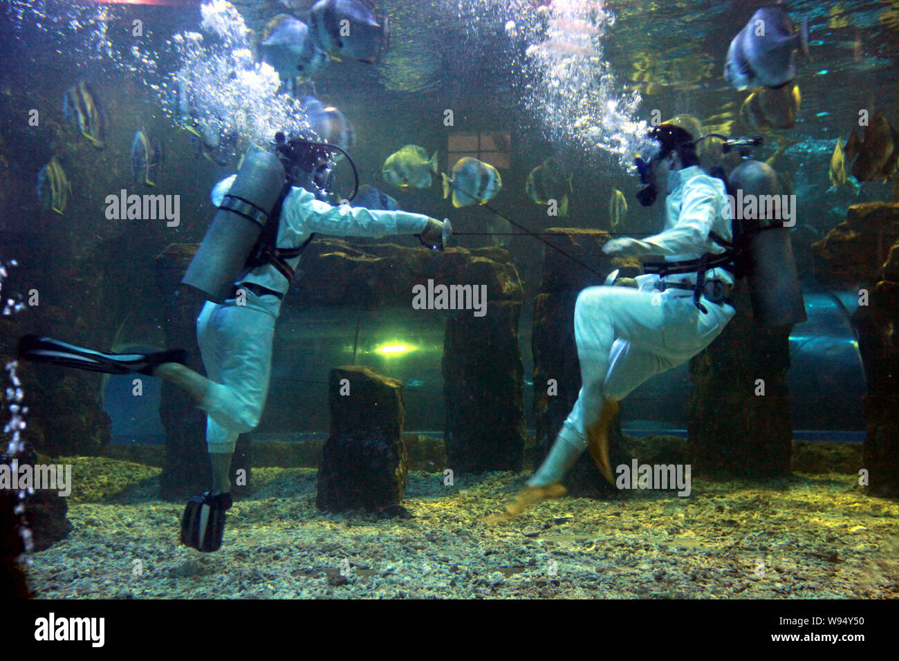 Two divers dressed in fencing costume perform in water during an ...