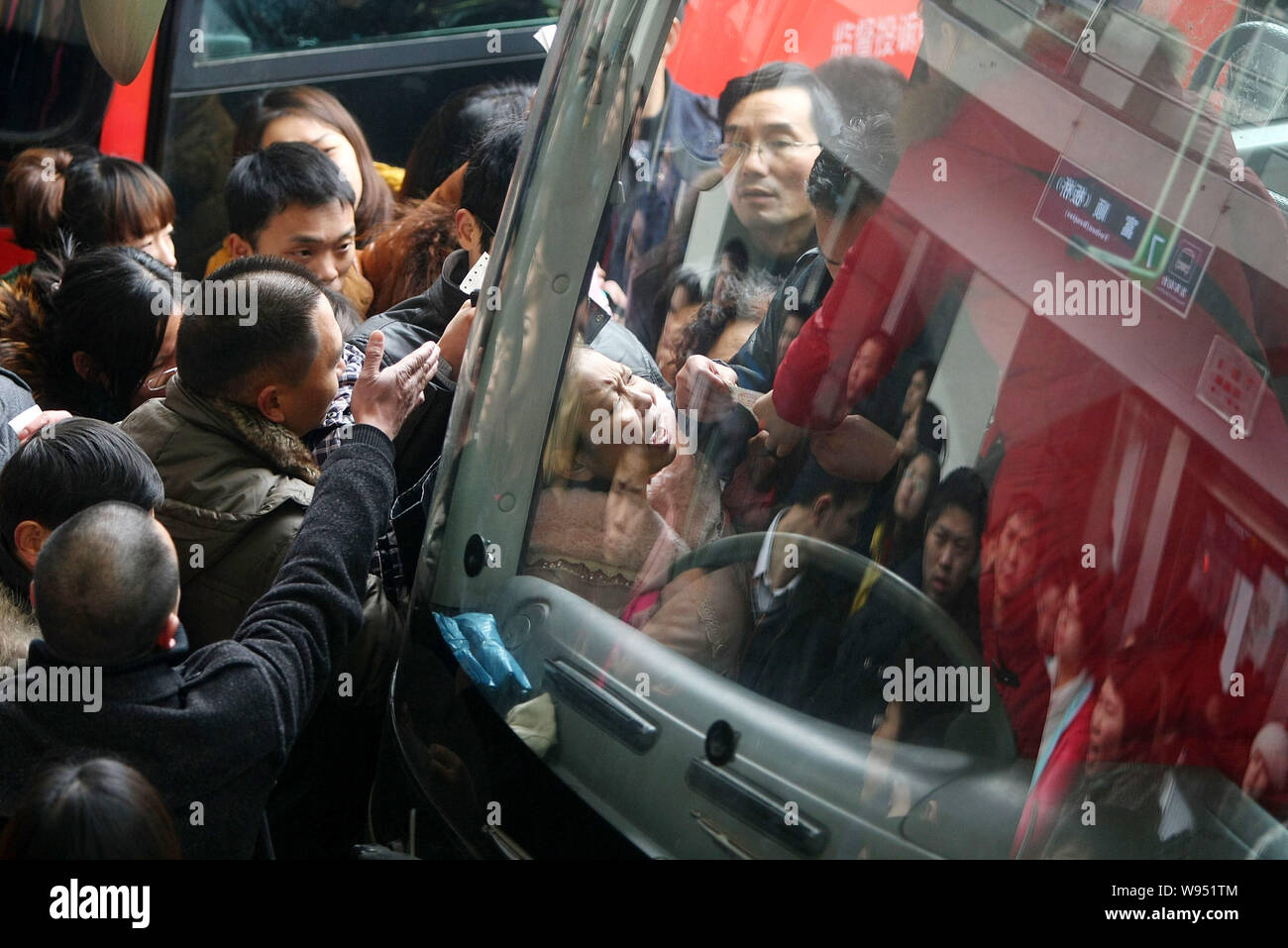 A crowd of passengers try to jam into a bus at a long-distance bus ...
