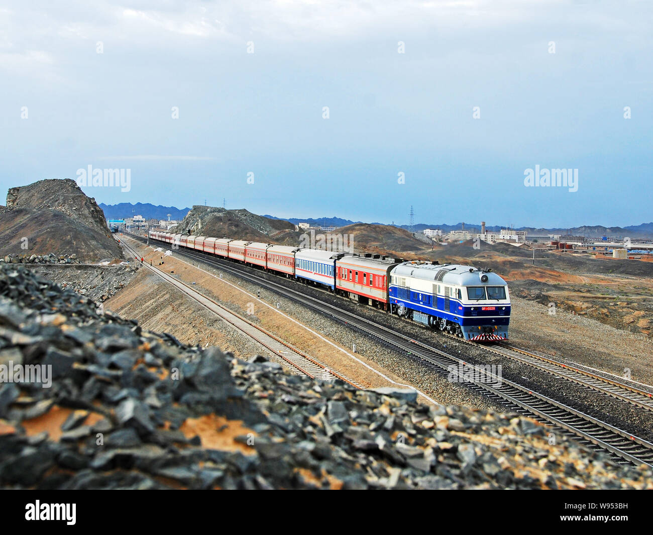 A passenger train passes by a mining area in Liuyuan town, Guazhou ...