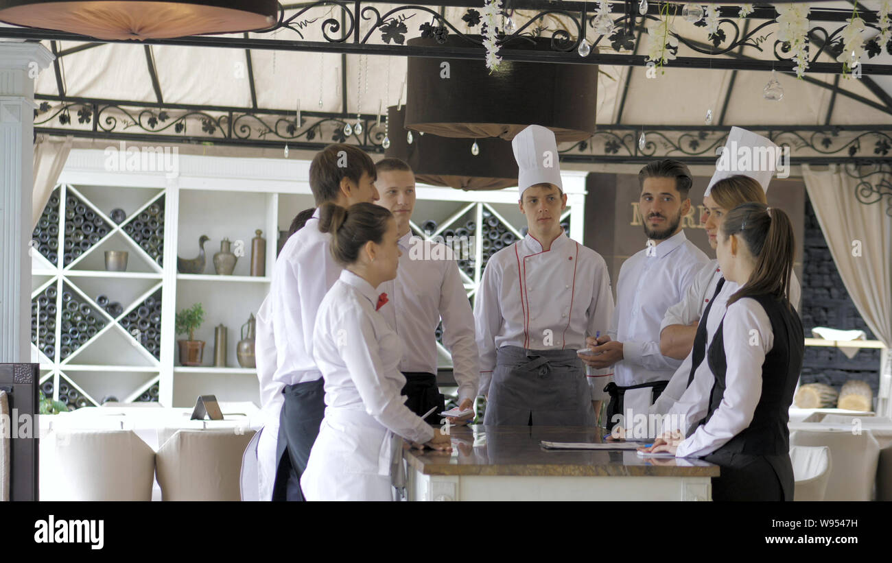 Restaurant manager and his staff in terrace. Interacting to head chef ...