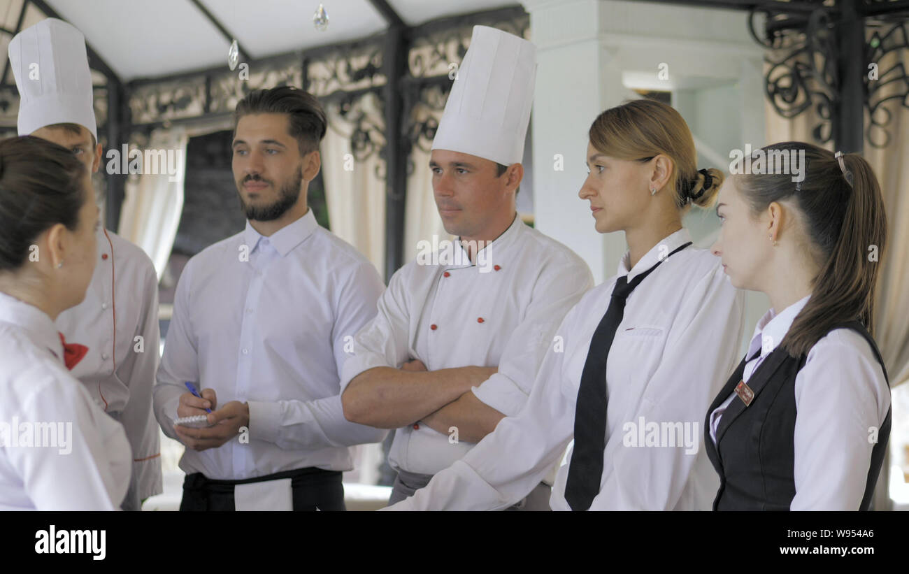 Restaurant manager and his staff in terrace. Interacting to head chef ...
