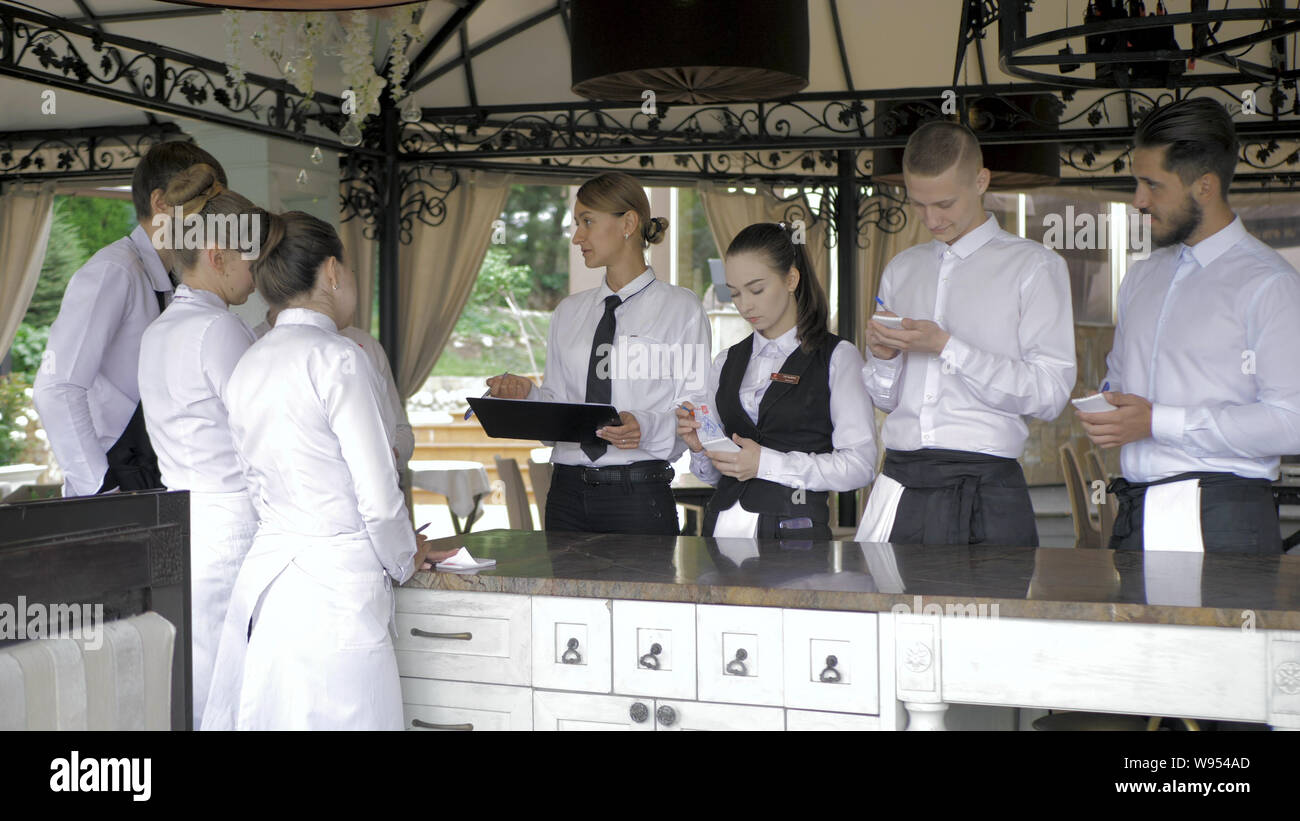 Restaurant manager and his staff in terrace. Interacting to head chef ...