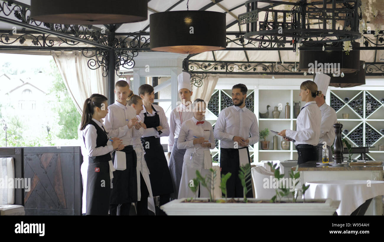 Restaurant manager and his staff in terrace. Interacting to head chef ...