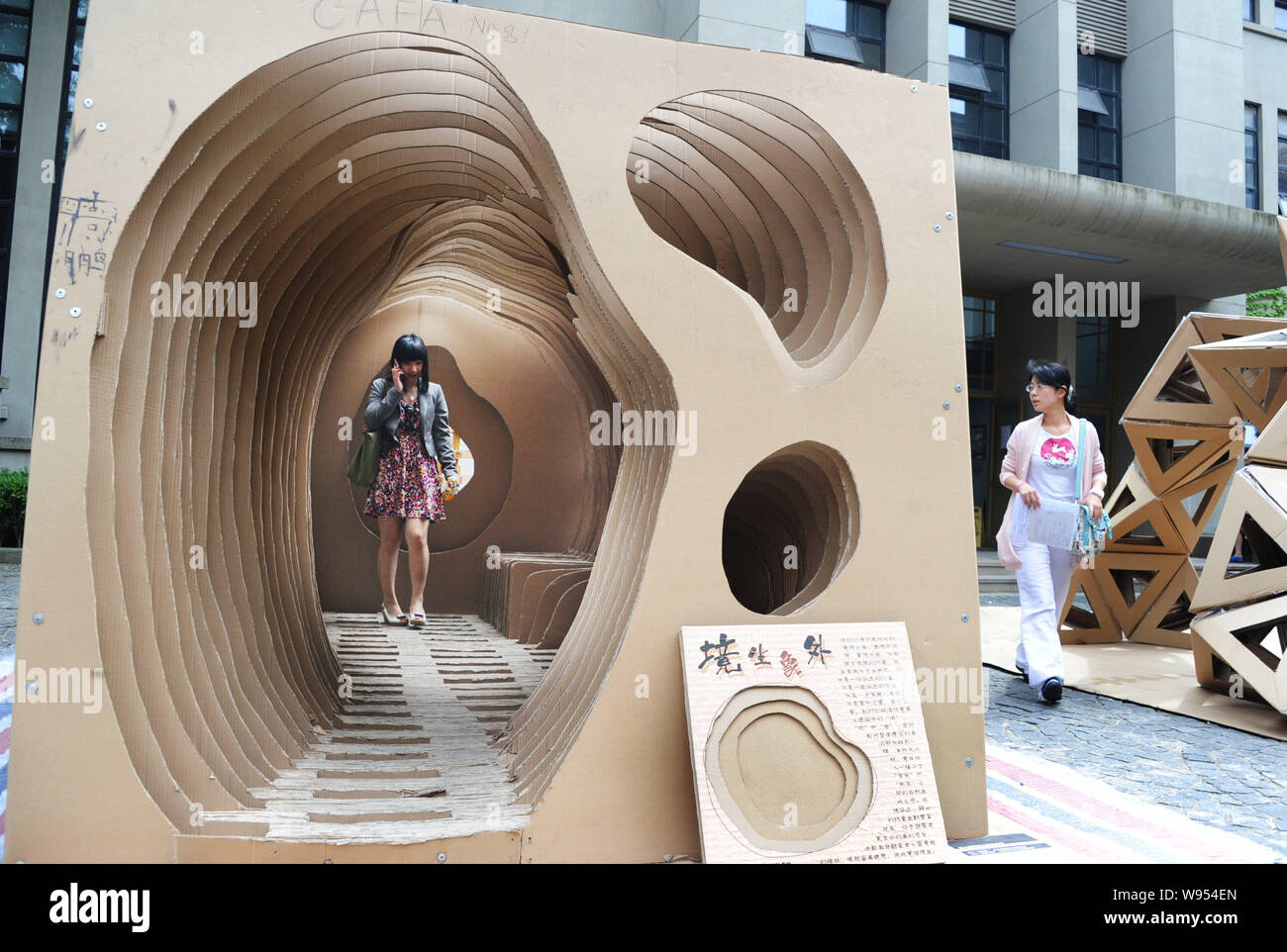 Visitors walk past cardboard building structures at Tongji University ...