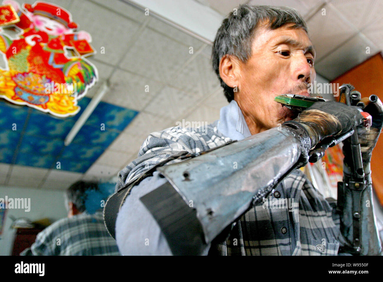 --File--Sun Jifa plays the harmonica with his self-made artificial ...